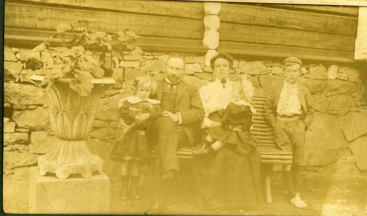 Familien William MacLean Homann sitter ute. Helen (1905) holder en katt ...
