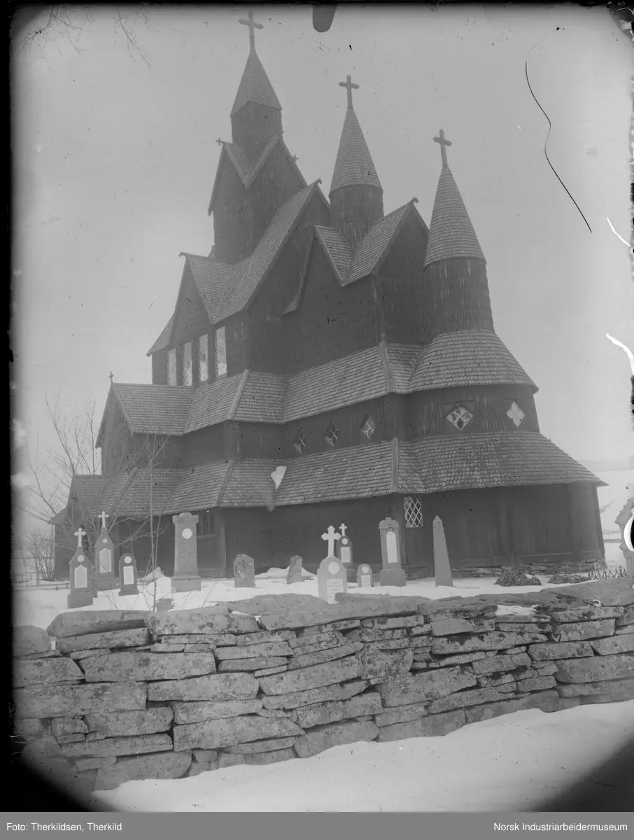 Heddal stavkirke. Kirkegård med gravstøtter foran kirken. Tørrmurt ...