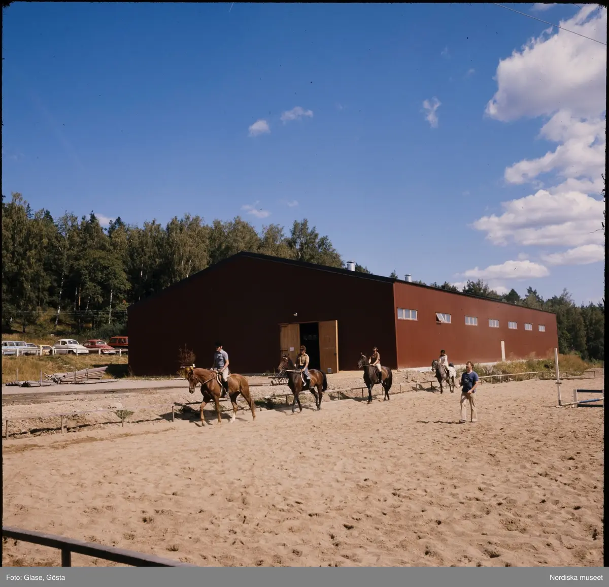 Ridskola. Elever rider framför ett ridhus. - Nordiska museet ...