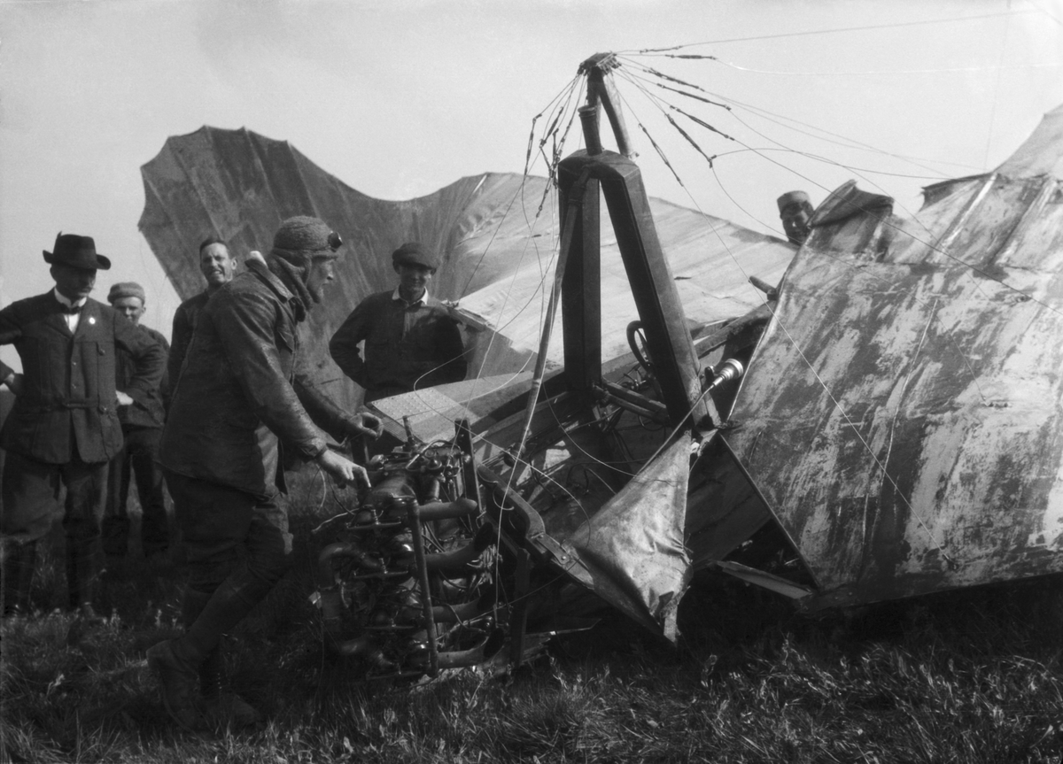 En flygare står vid nosen på ett havererat militärt flygplan Etrich ...
