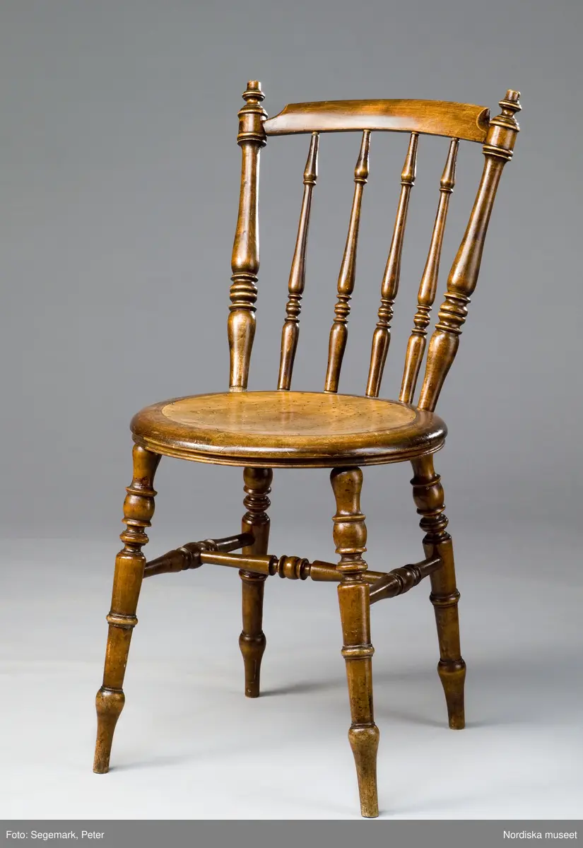 Pinnstol med svarvade ryggstolpar och ben. Rund sits med borrade hål i ...