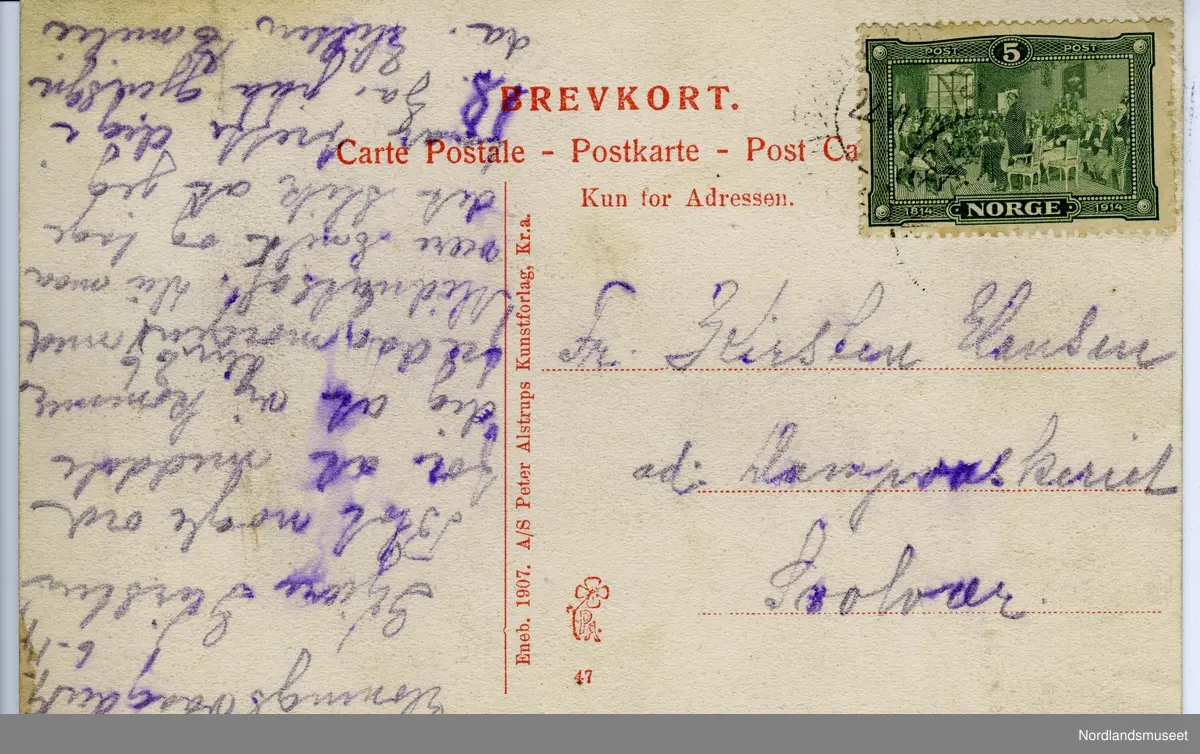 Postkort som viser kvinne i bunad. Hun står i en gjerdeåpning og holder ...