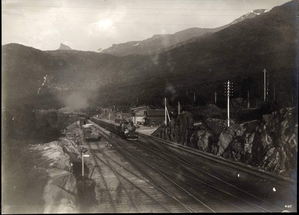 Gamle Narvik Jernbanestasjon med tog med damlok på tur ned mot kaiene ...