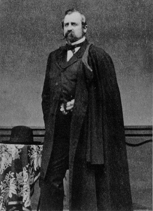 Porträtt av kapten Broberg i helfigur. Han står med en ytterrock ...