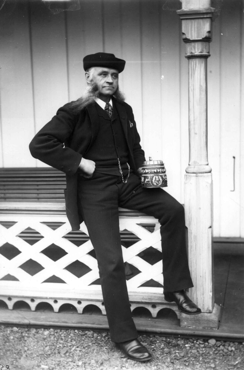 Portrett, Peter Simonsen (1831-95), sittende utendørs på utskåret ...